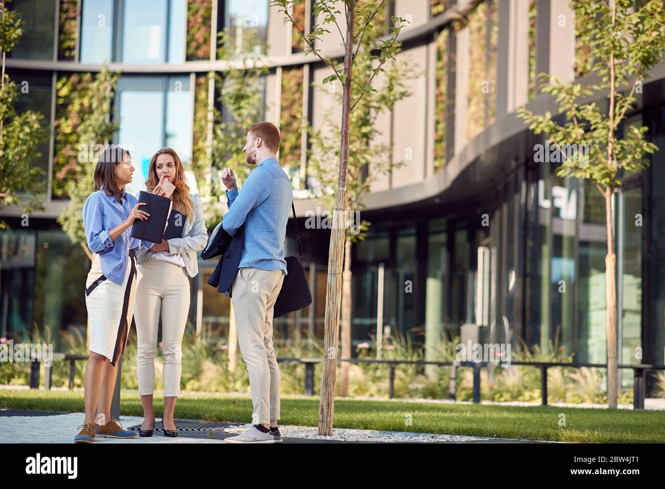Women and man coworkers talking outside the building Stock Photo - Alamy