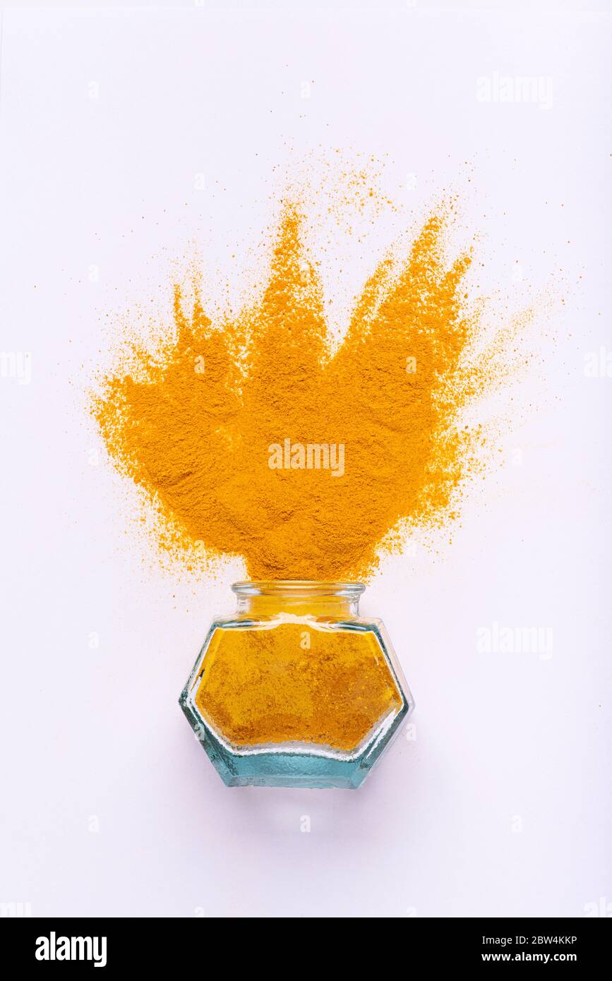 from the glass bowl a sprinkling of turmeric on a white background ...