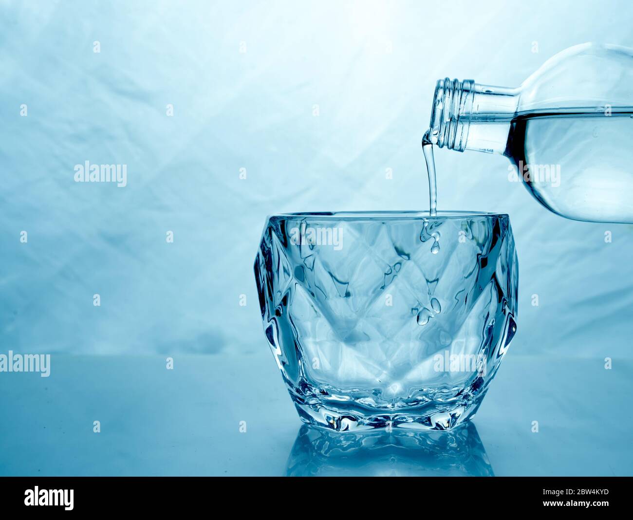fresh clean water is poured from a bottle into a glass cup. Light ...