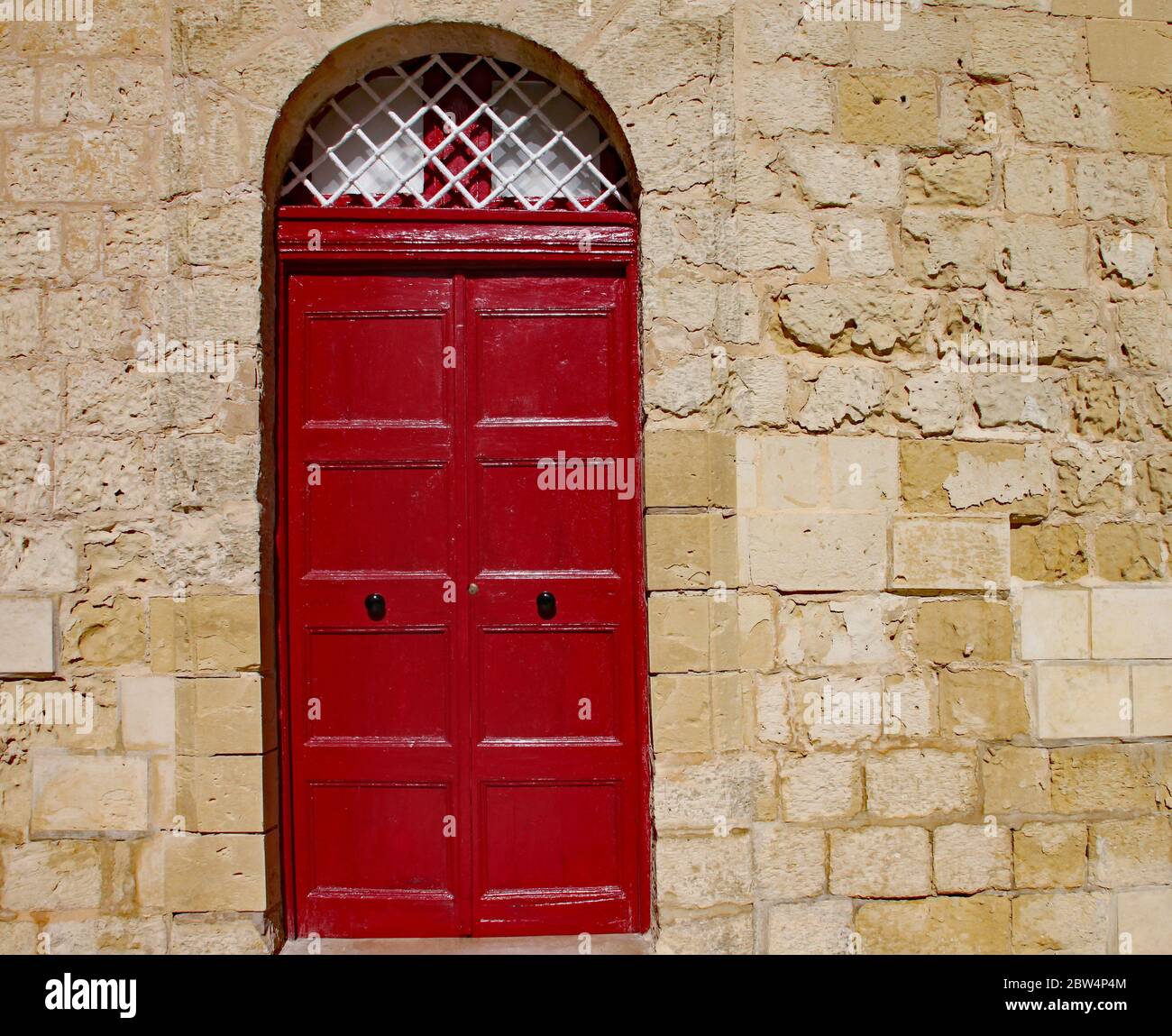Freshly painted red door in a crumbling limestone wall in Sliema, Malta ...