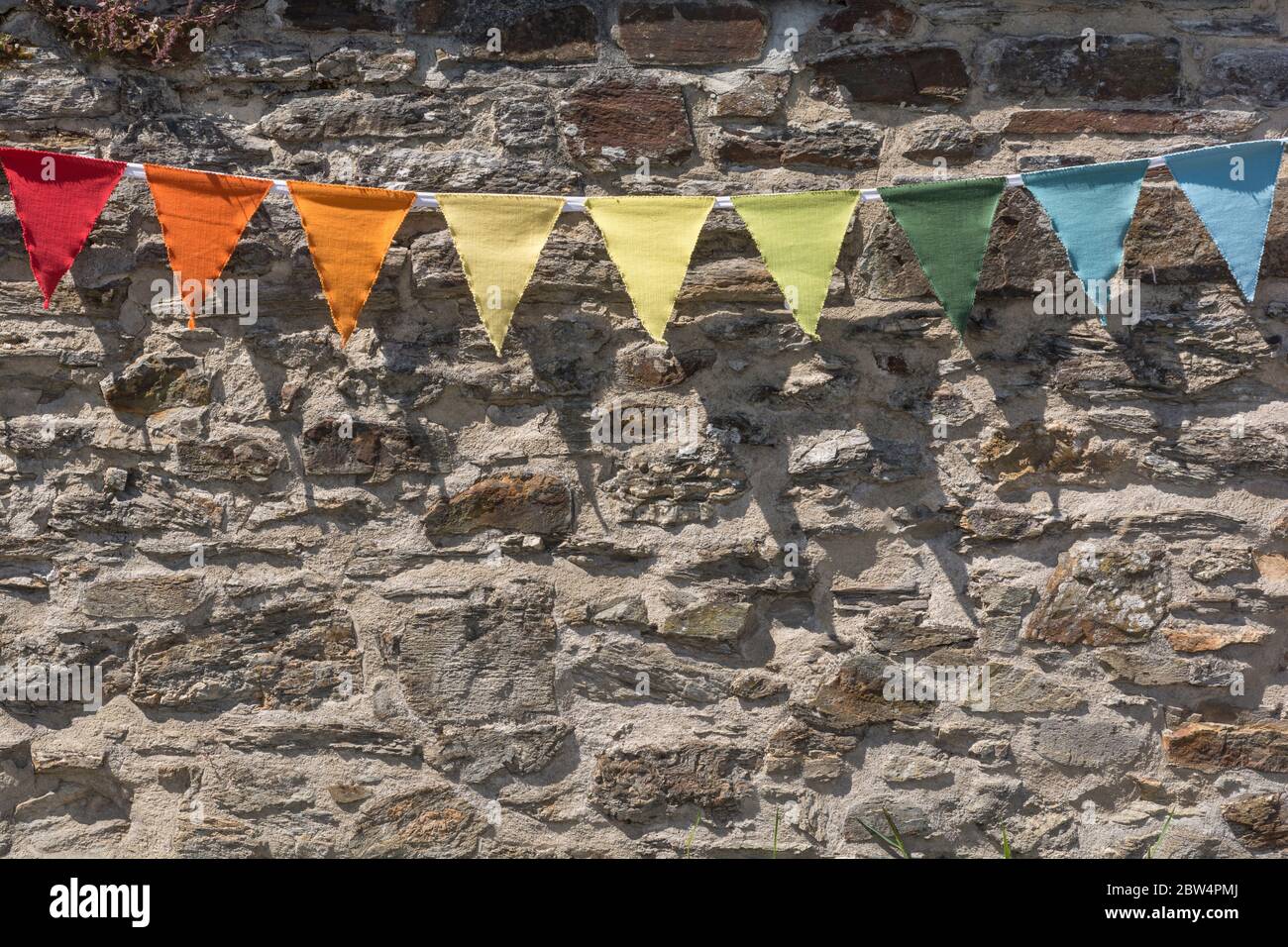 Colourful fabric bunting flags isolated against house wall. Metaphor ...