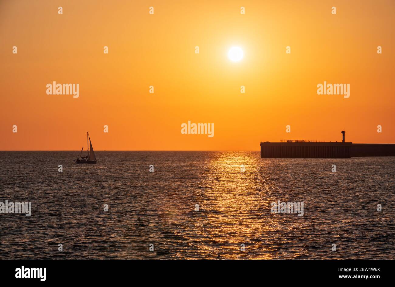 Beautiful yellow and orange sunset over the sea. The sun goes down over the sea. Silhouette of ...