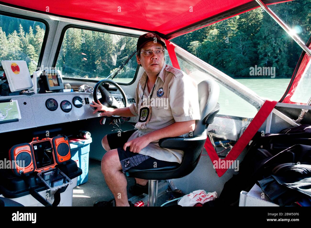 An indigenous Guardian Watchman in a motorboat patrolling Owikeno Lake ...