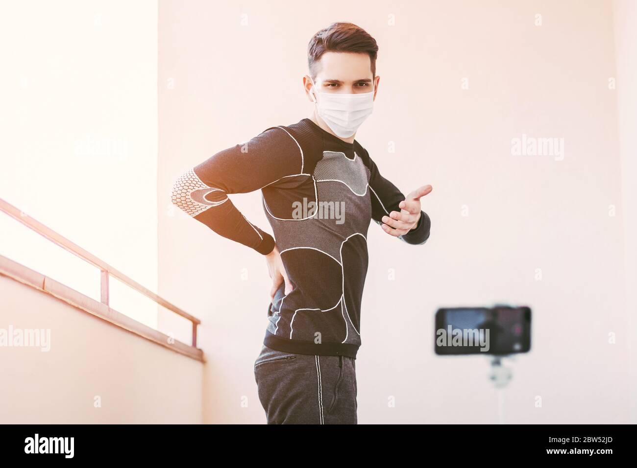 Confident sports man in medical face mask stretching muscles while ...