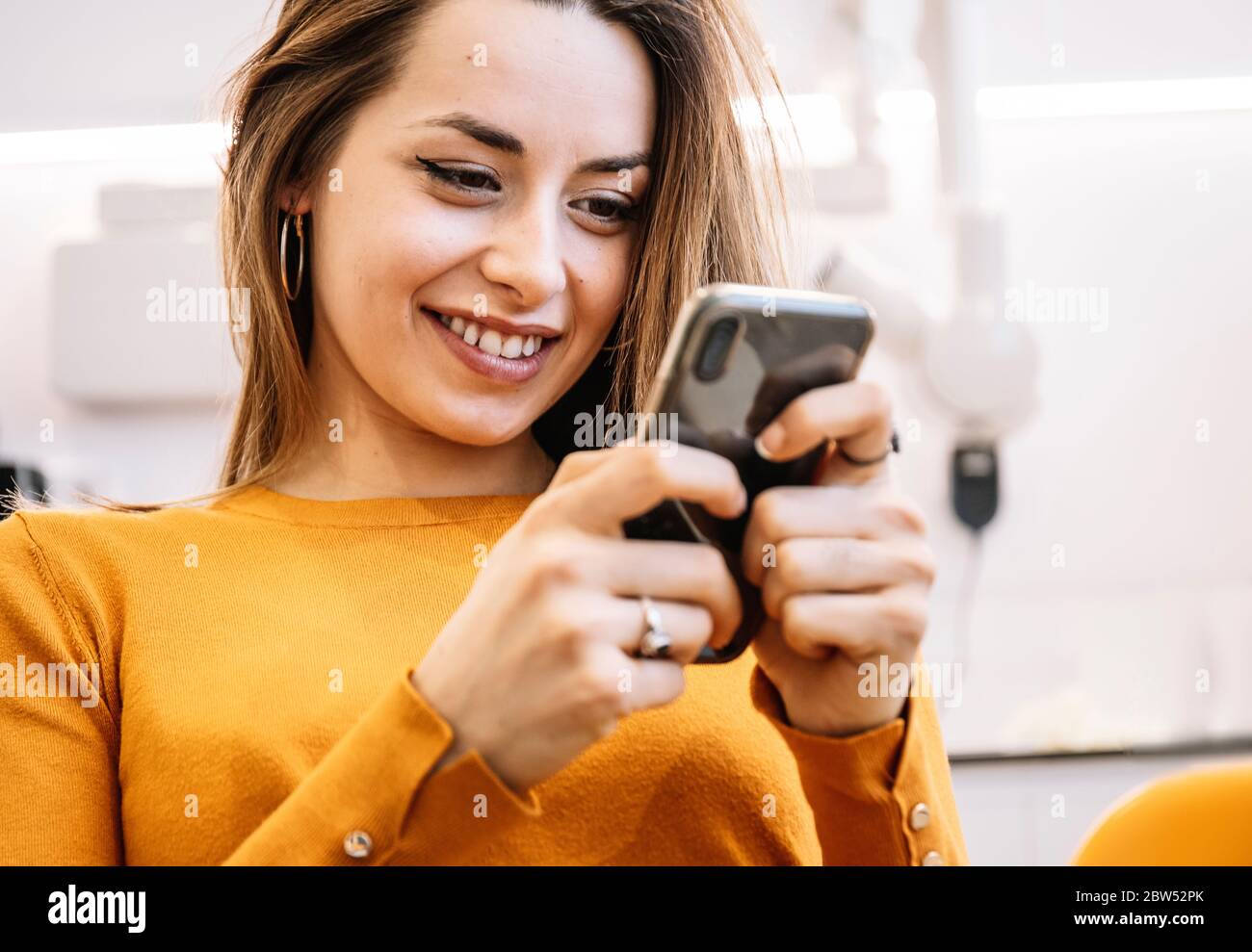 Happy woman smiling and browsing social media on smartphone while ...