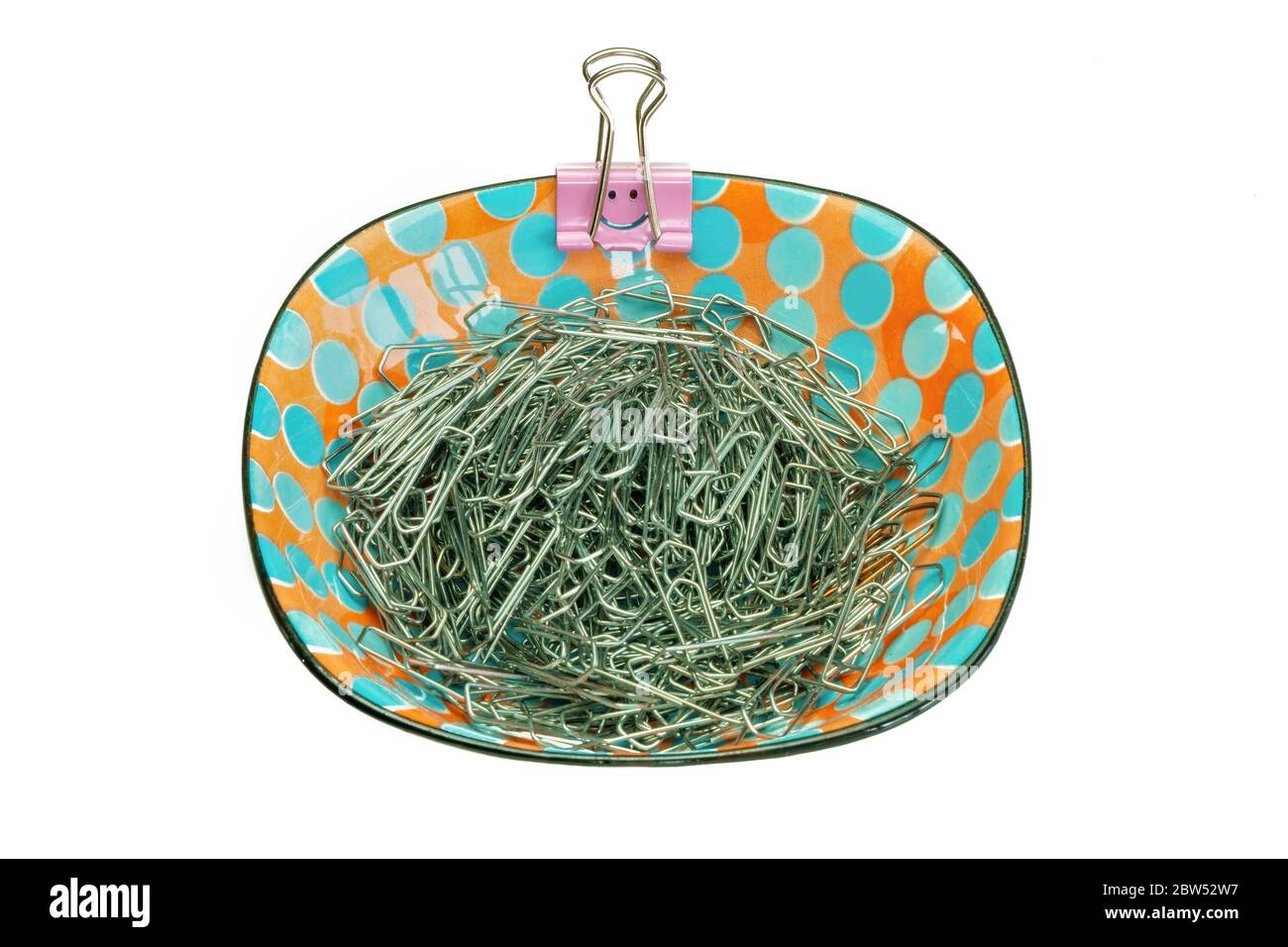 A porcelain bowl with paper clips and a pink smiley paper clip on the ...