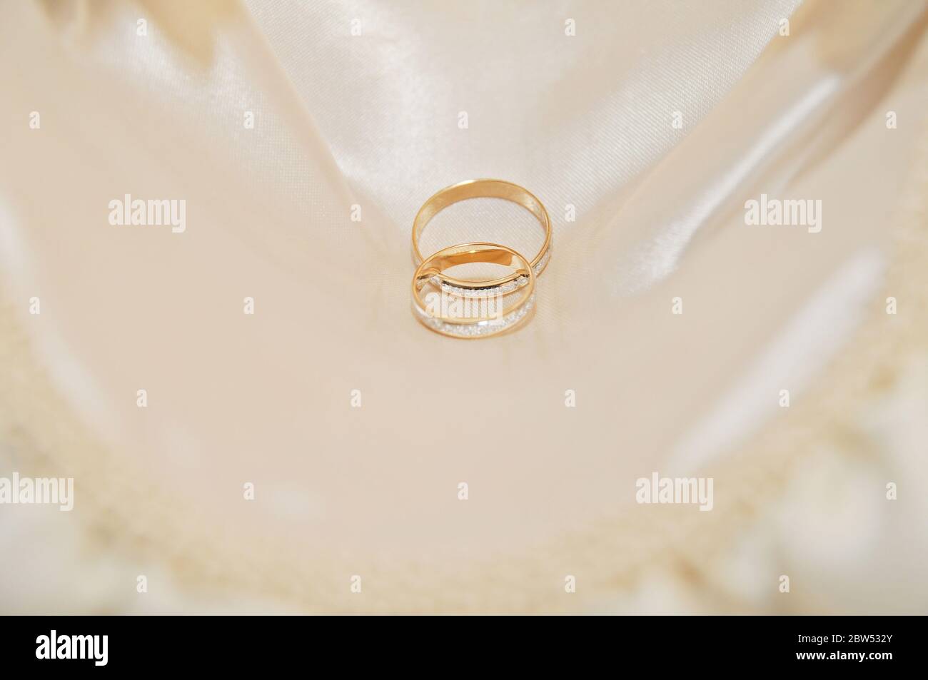 Reflection inside a gold diamond ring next to another ring with a satin ...