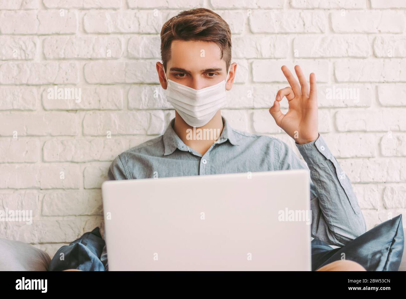 Young hipster man in protective face mask showing okay sign, while ...