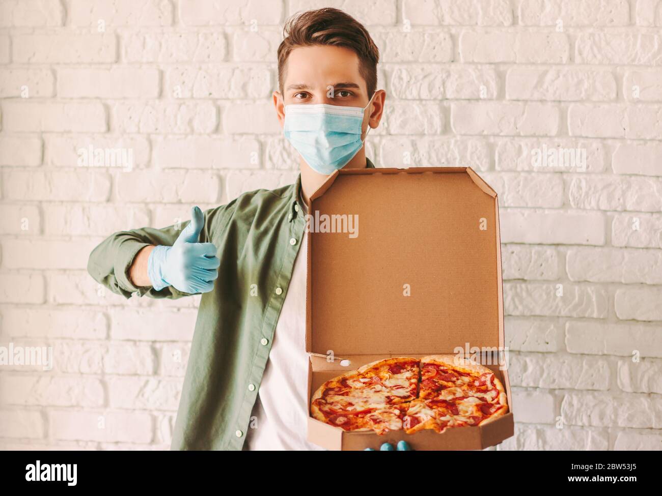 Hipster man pizza delivery service worker in medical face mask and ...