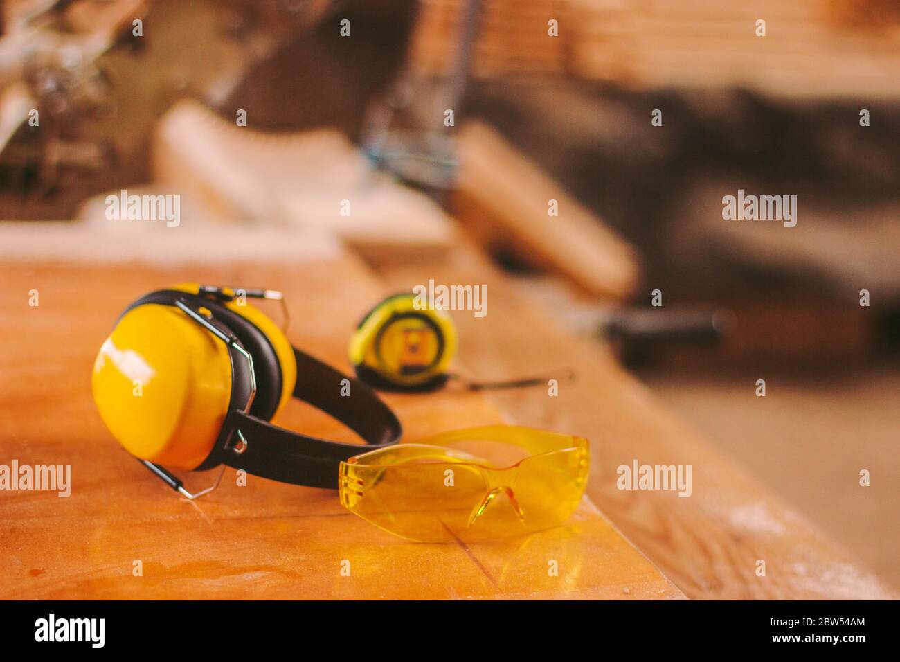 Closeup of protective headphones and glasses on workman table at wood ...
