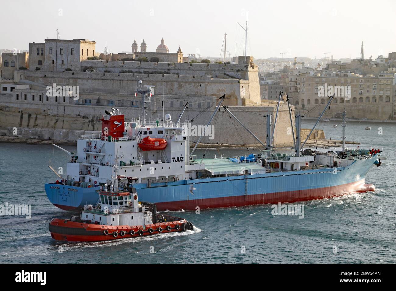 VALLETTA, MALTA - NOVEMBER 16TH 2019: A cargo ship is escorted by a ...