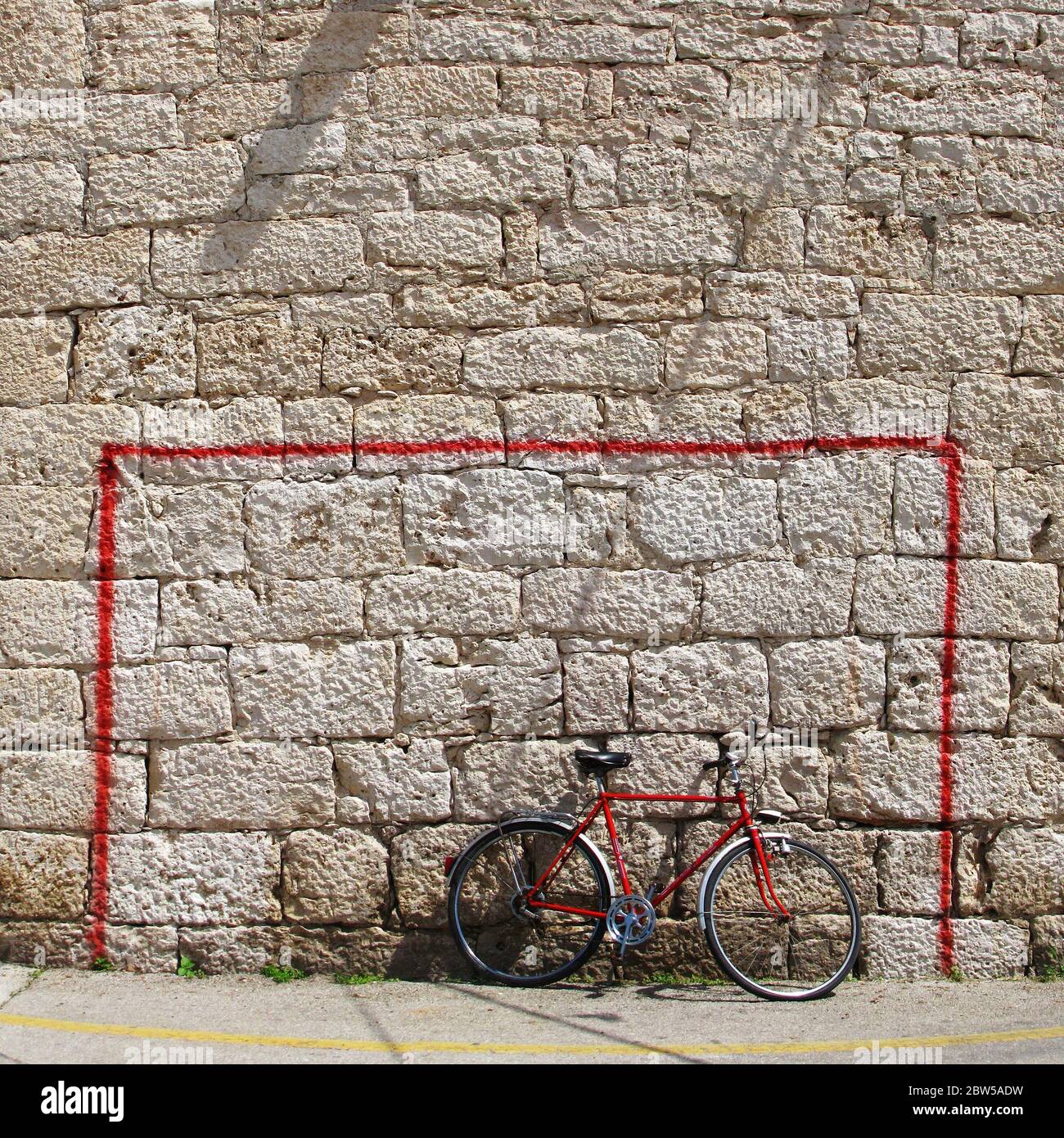 Red bicycle in front of stone wall on hot spring day framed by red ...
