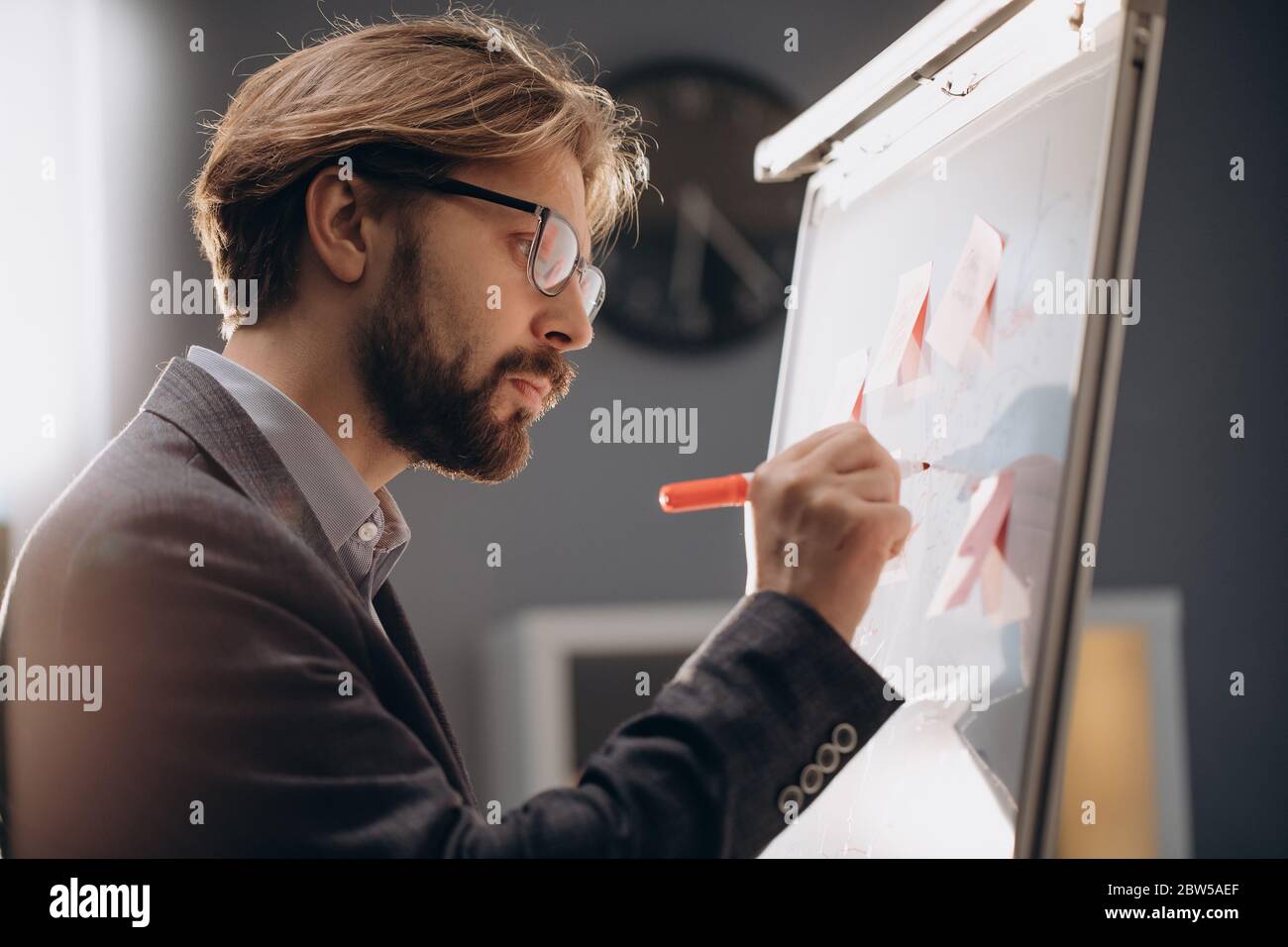 Concentrated bearded man drawing graphs on flipchart Stock Photo - Alamy
