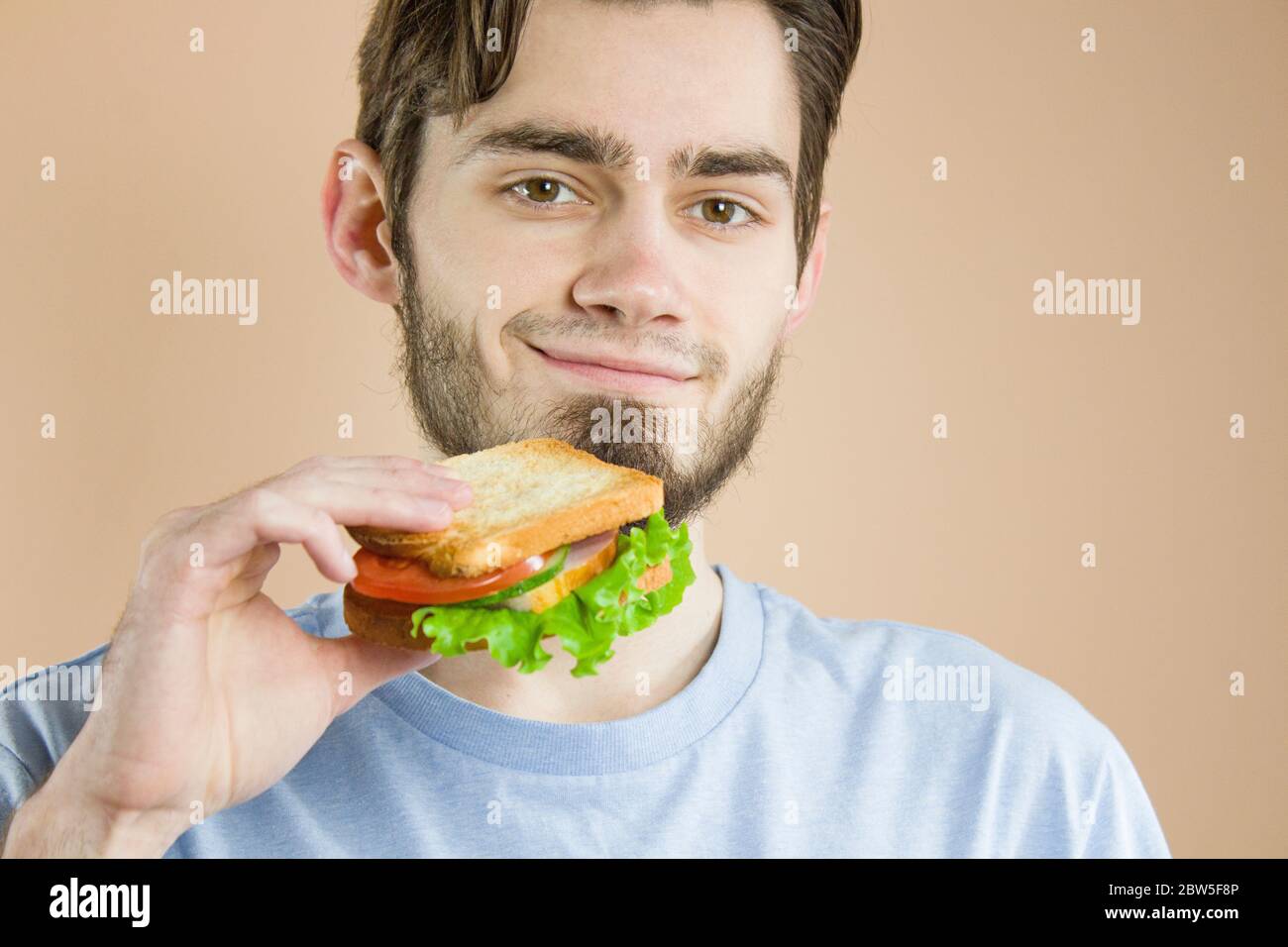 guy with a beard eats a delicious toast or hamburger. Man Stock Photo ...