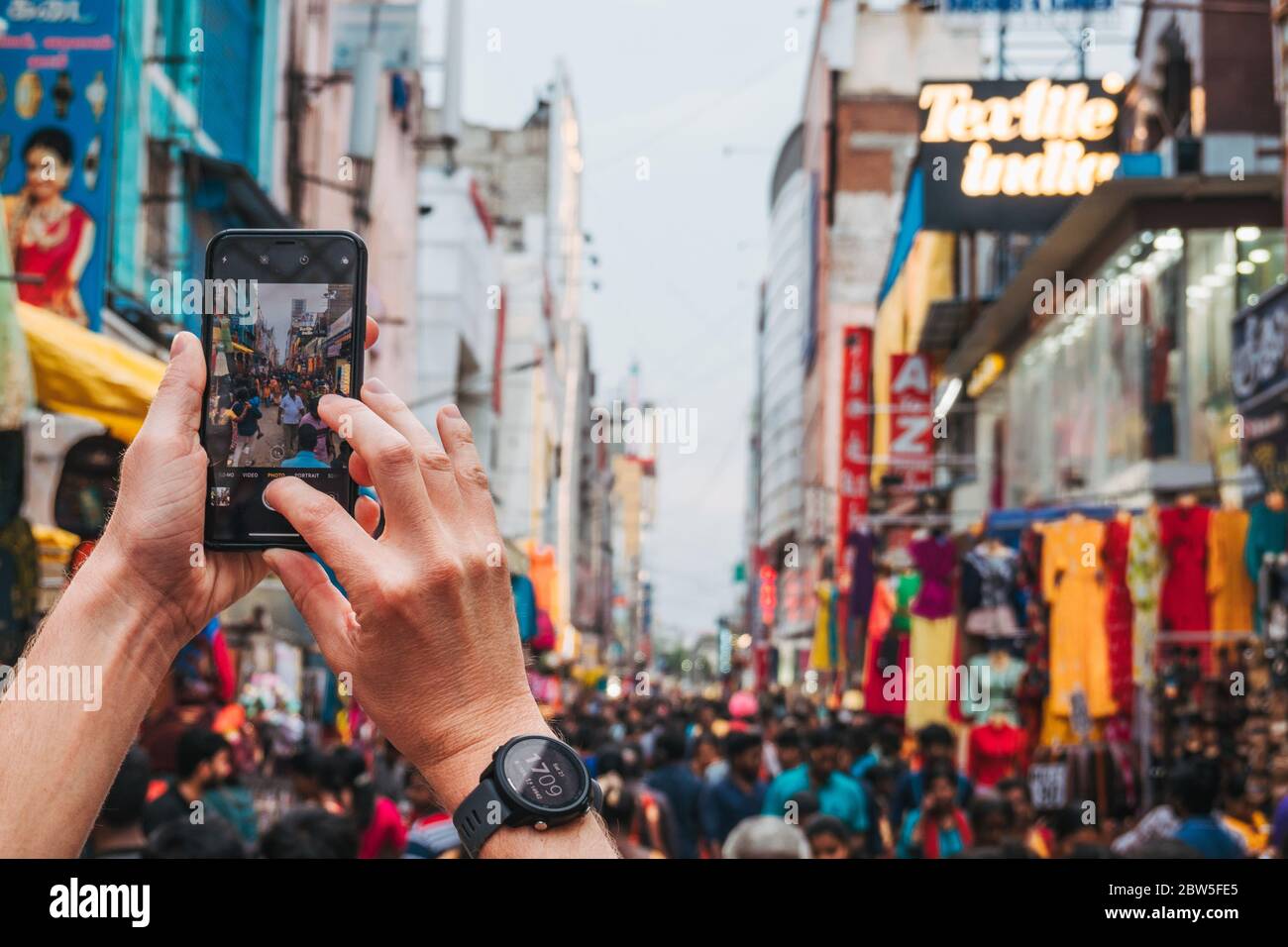 A tourist uses their phone to take a photo of a busy Ranganathan Street ...