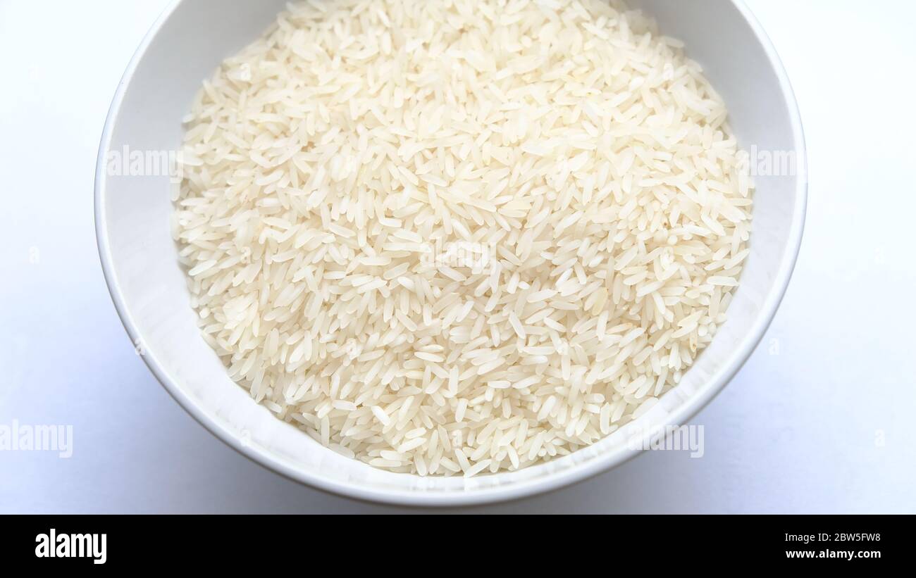 A bowl of uncooked white rice against a white background Stock Photo ...
