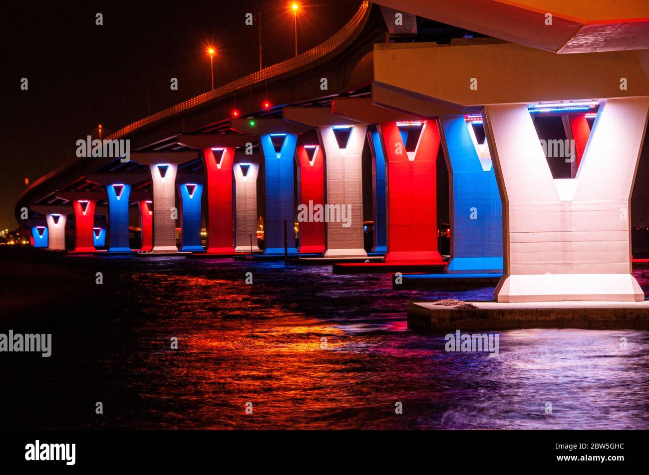 A night photograph of a bridge illuminated by red, white and blue ...