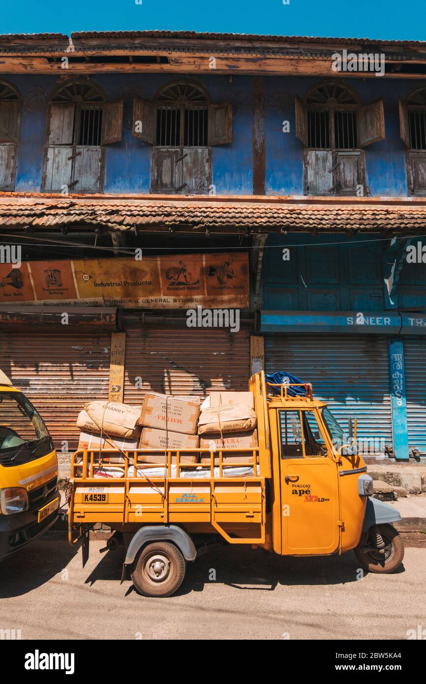 A cargo auto-rickshaw loaded with bags and boxes in front of a colonial ...