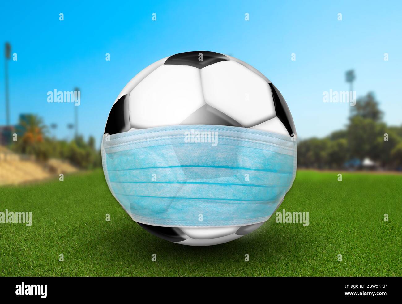 Soccer ball with a surgical mask in a soccer field with green grass ...