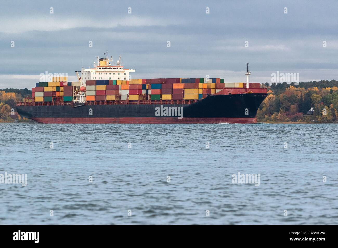 Container cargo ship cruising near a house along the river Stock Photo ...