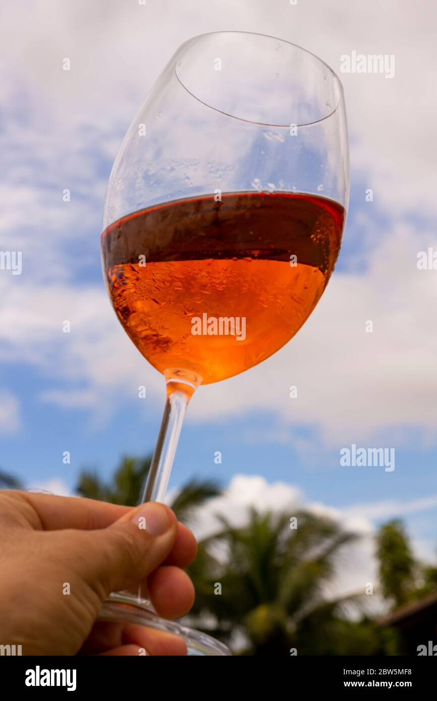 Crystal glass with fresh rosé wine for making a toast raised to heaven ...