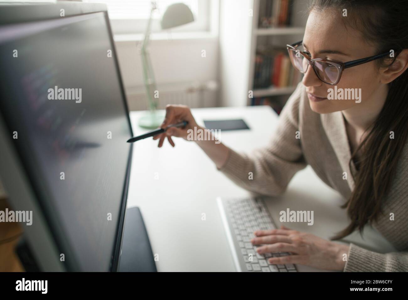 Young woman programming at her home office. Female programmer ponting ...