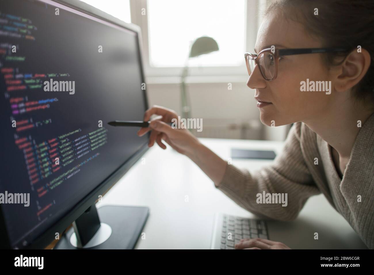 Young woman programming at her home office. Female programmer ponting ...