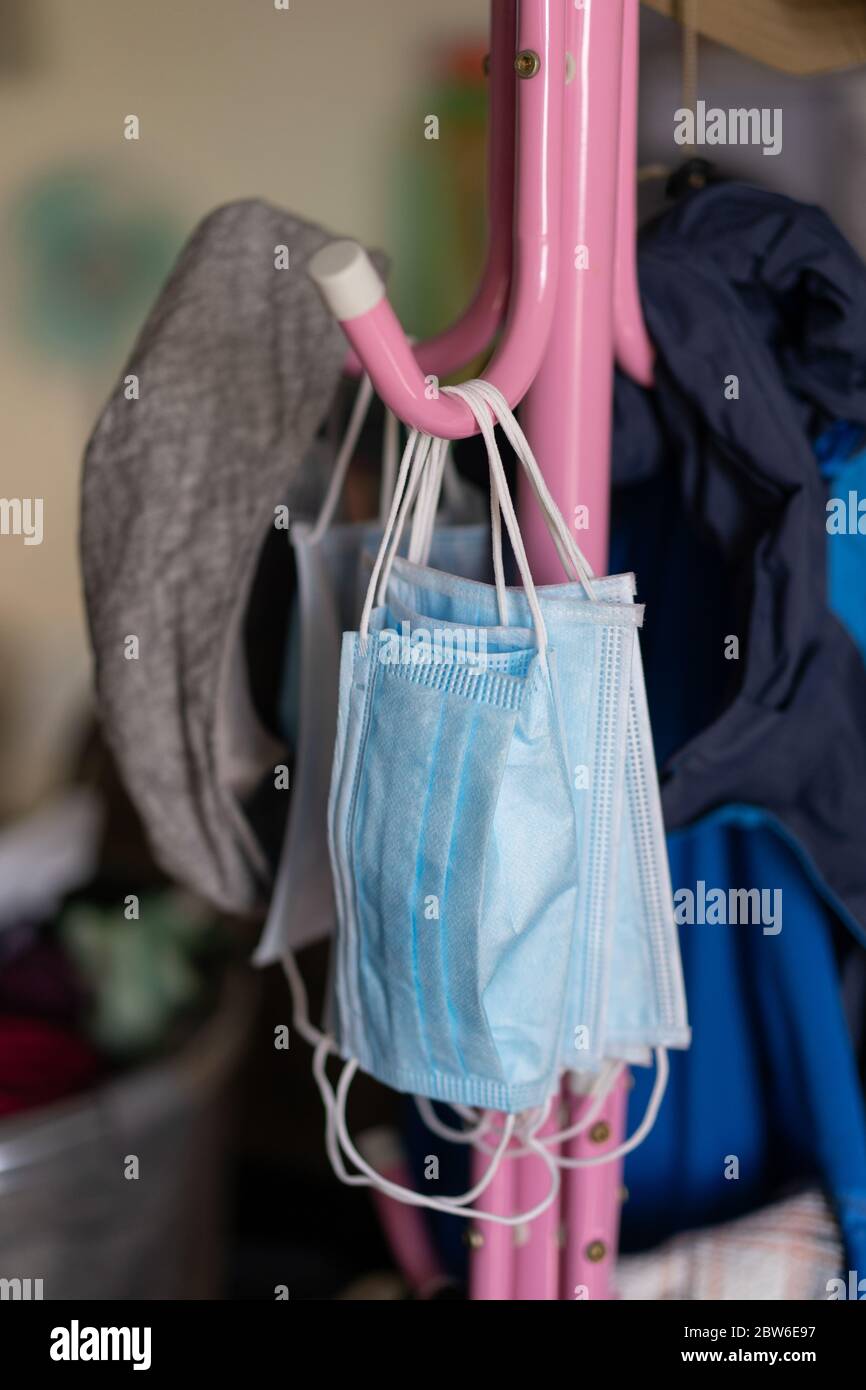 Surgical face masks hanging on a household clothes hanger depicting a ...