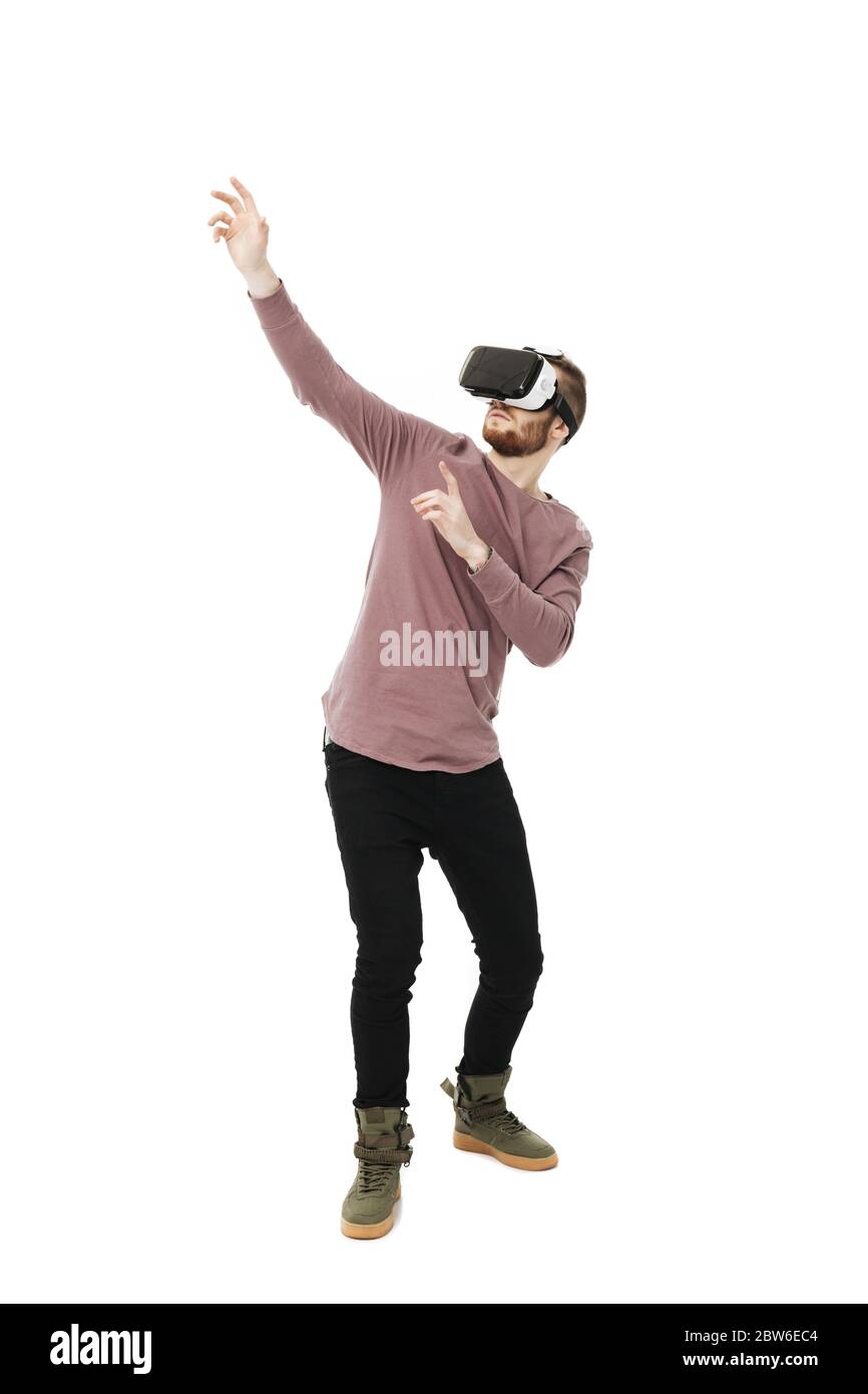 Young man standing in virtual reality glasses on white background. Cool ...