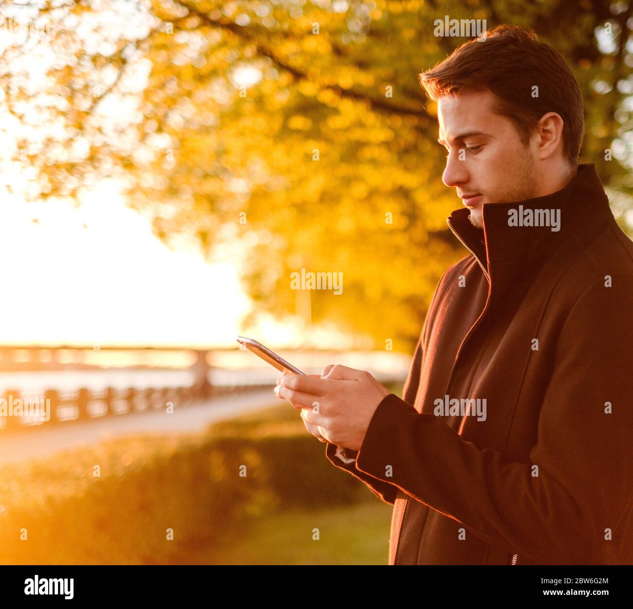 Man in coat with mobile phone outdoor Stock Photo - Alamy