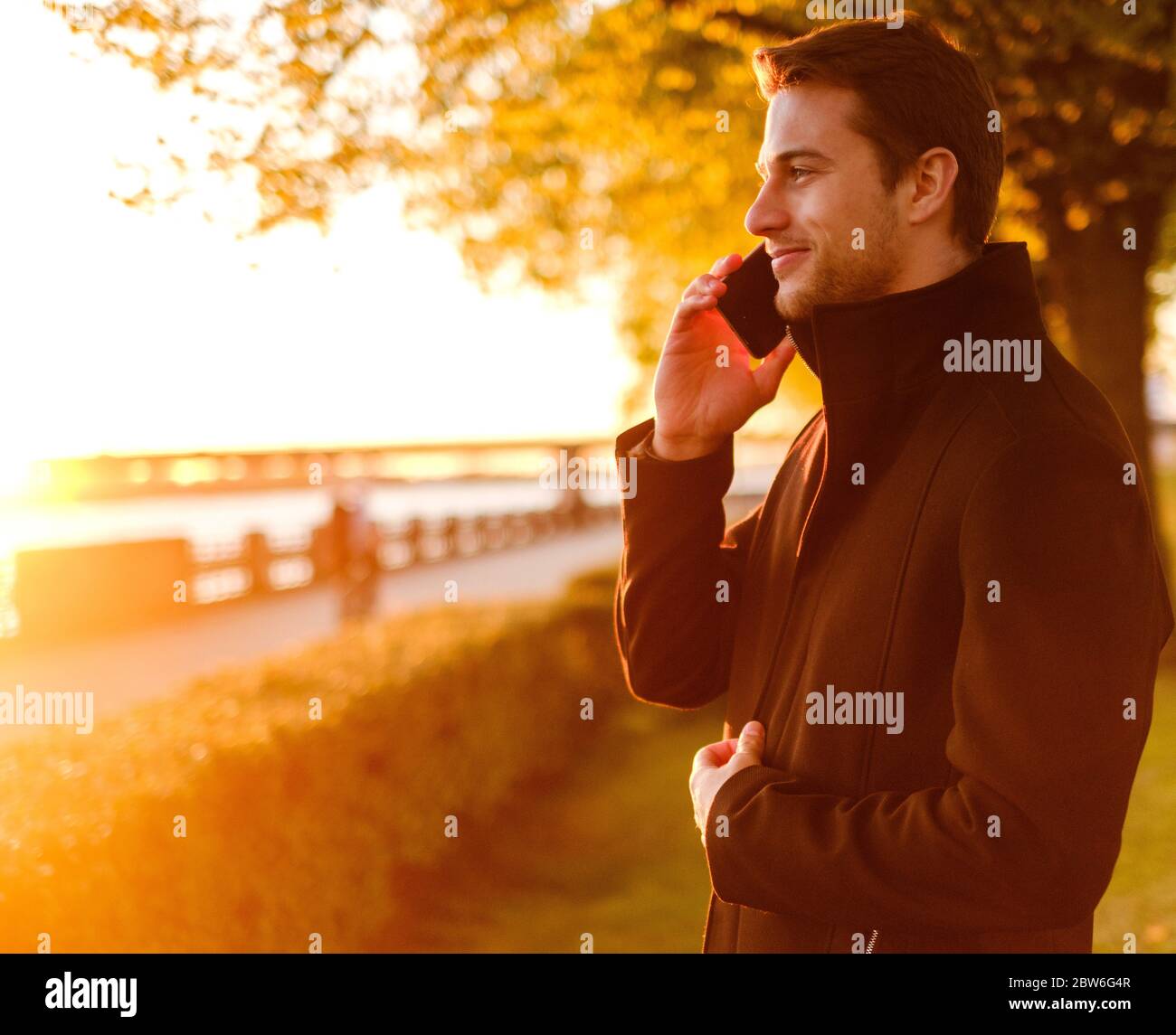 Man in coat with mobile phone outdoor Stock Photo - Alamy