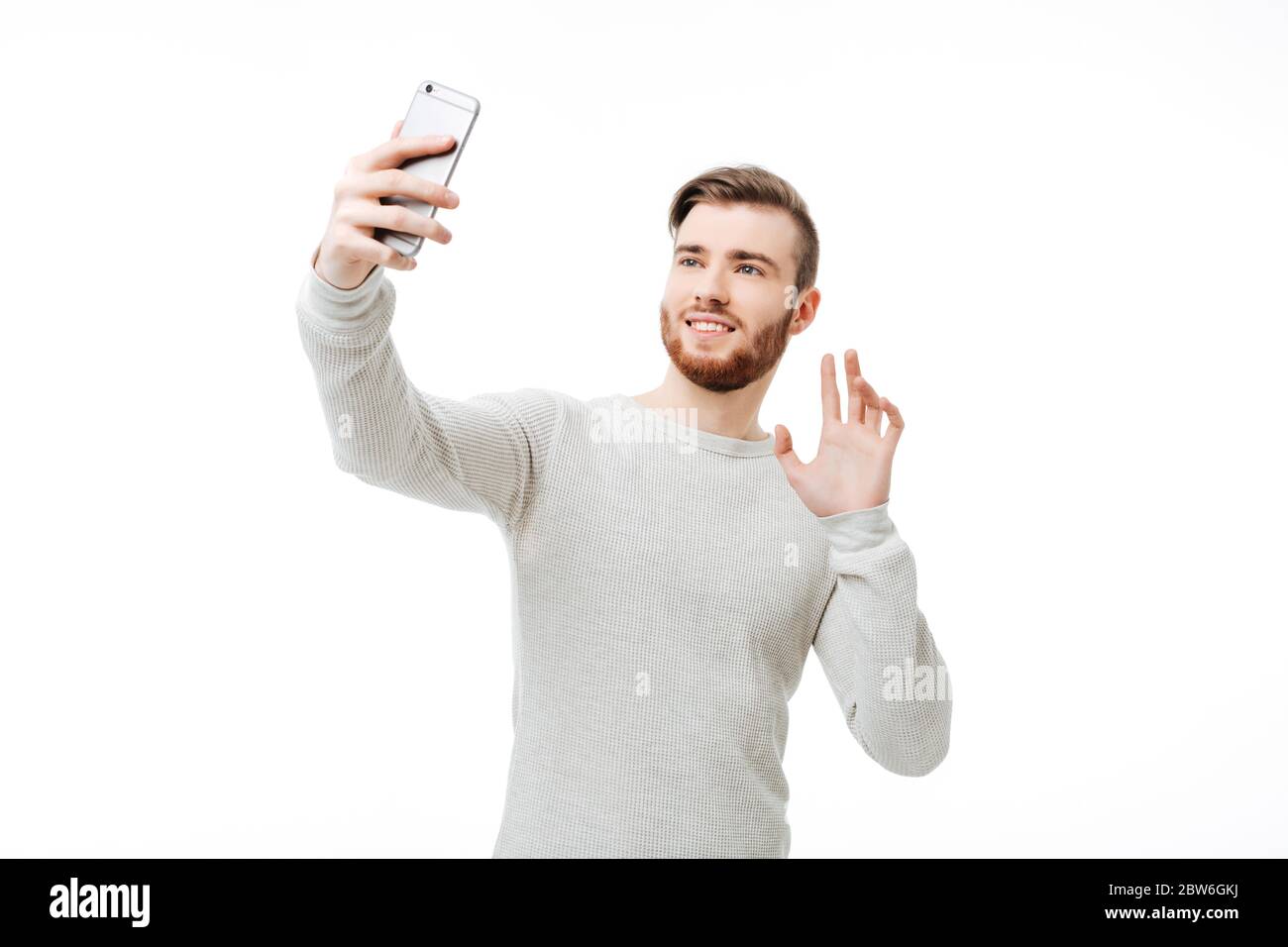 Cheerful handsome man taking selfie and waving hello to the front ...