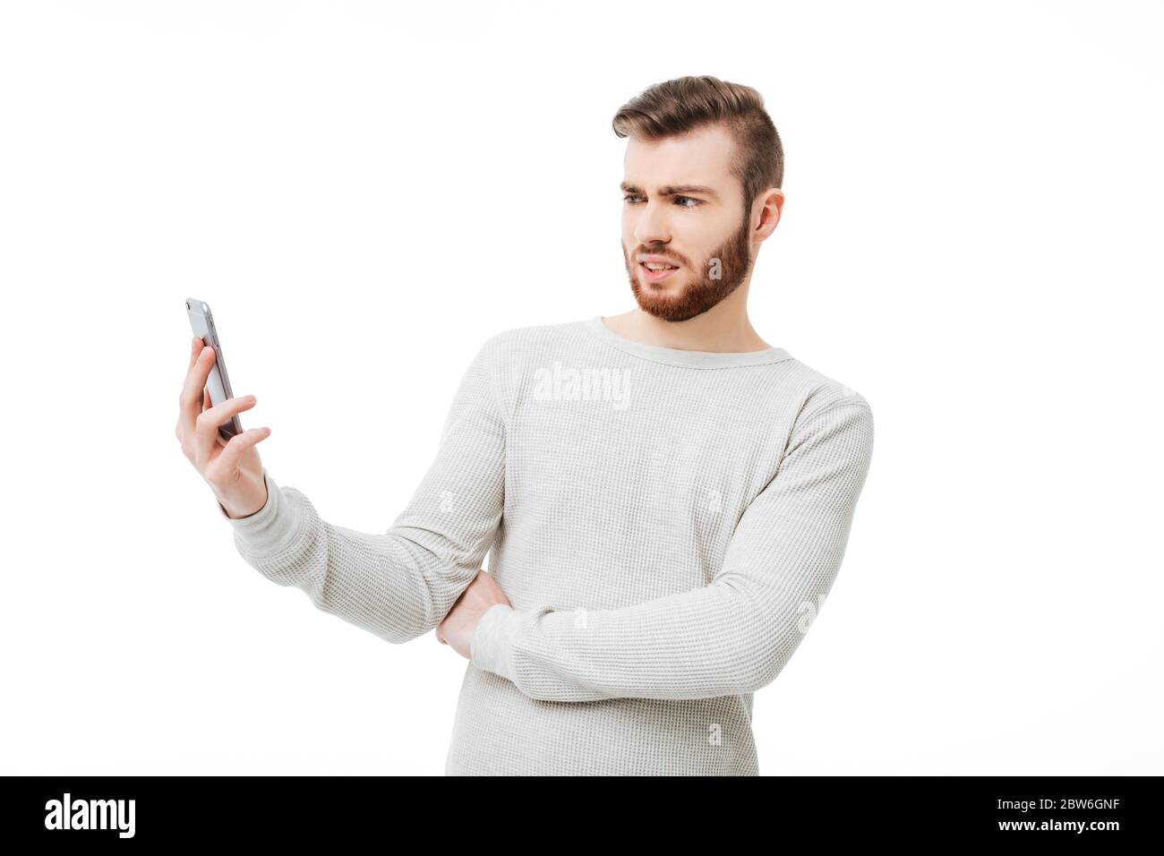 Young angry man looking with disgust on his smartphone isolated. Casual ...