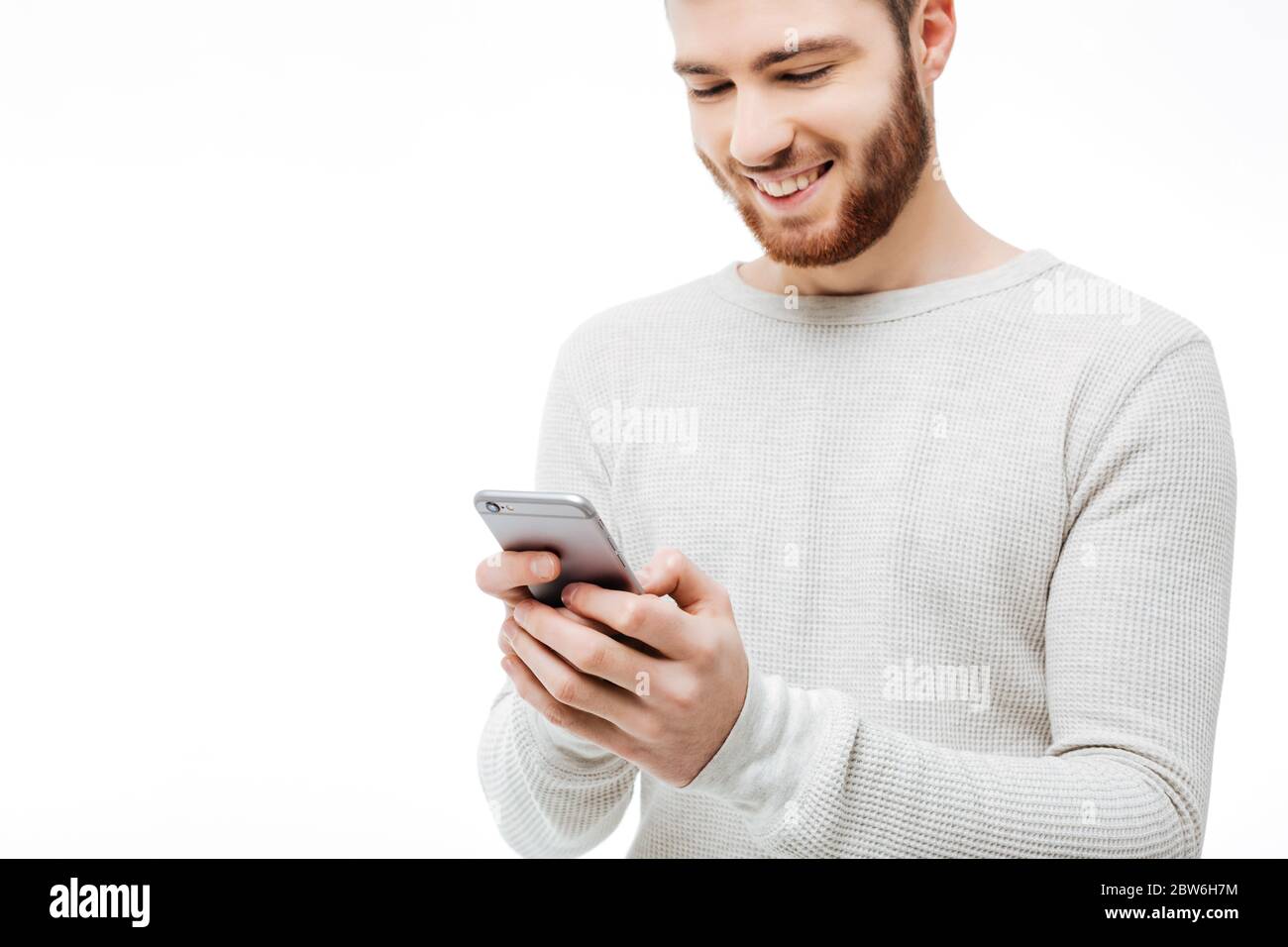 Happy guy typing message on the smartphone isolated. Handsome cheerful ...