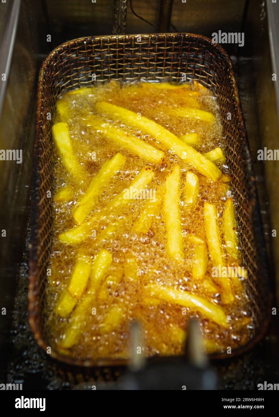 French fries boiling in hot oil in fast food restaurant kitchen for ...