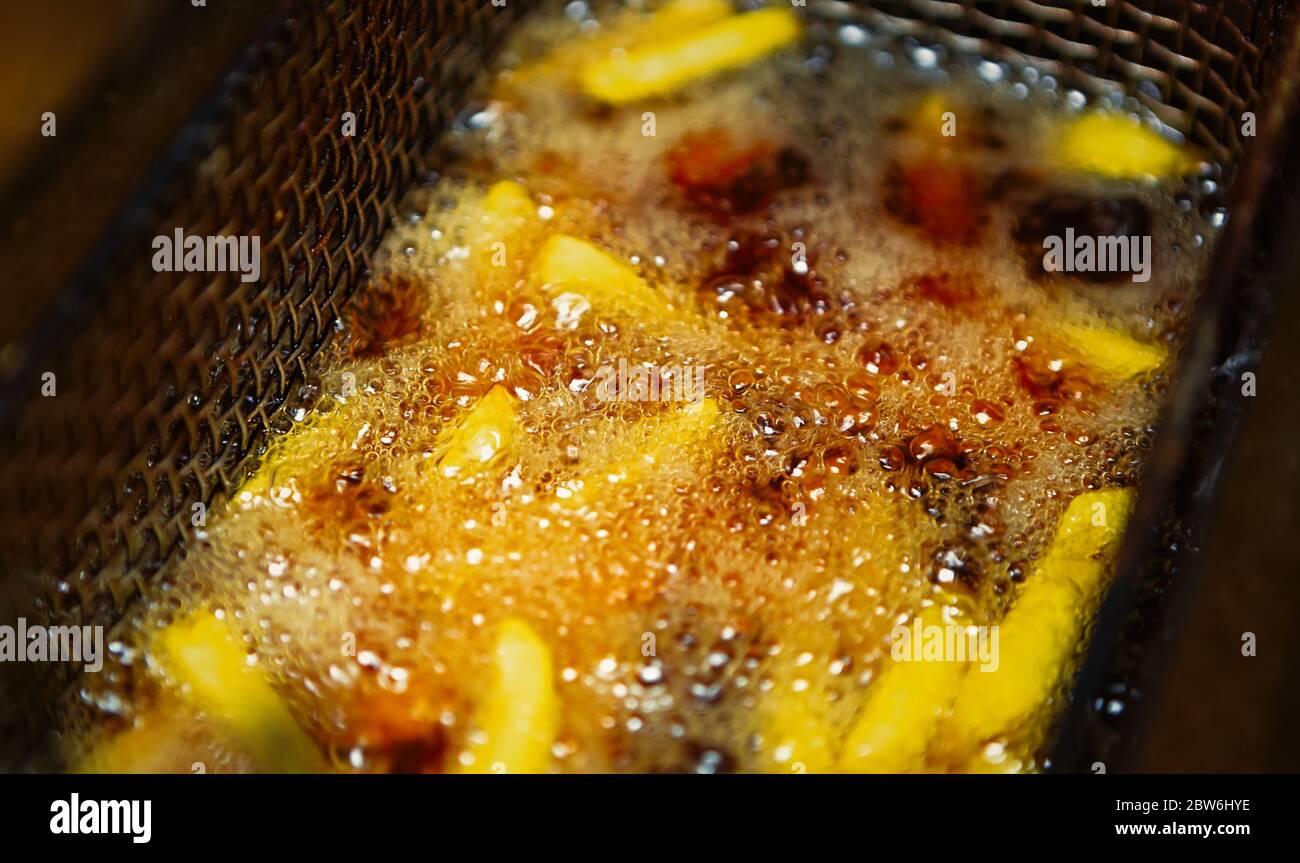French fries cooking in hot oil.Fast food restaurant cookes potato ...