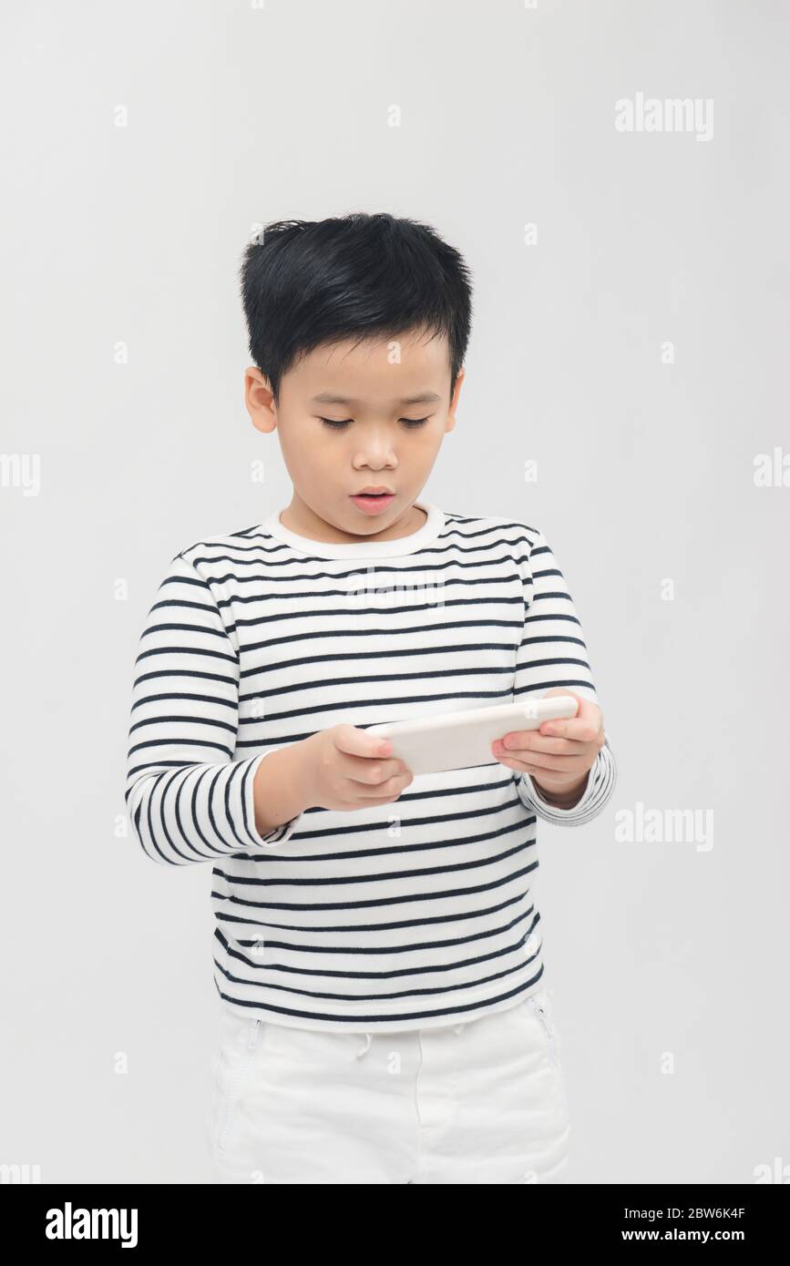 Portrait of an amused cute little kid playing games on smartphone ...