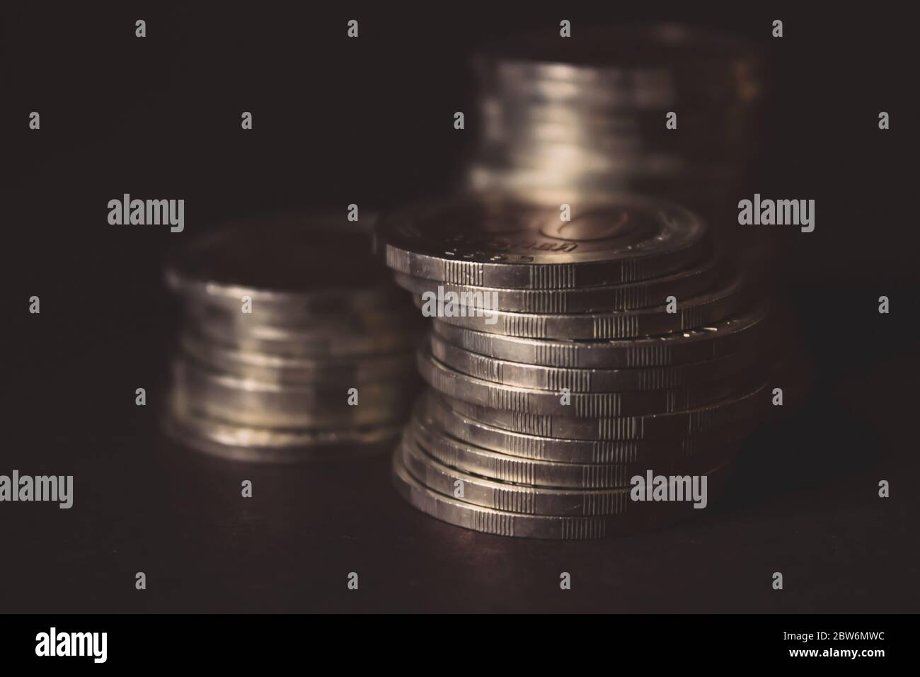 Coins stacked on each other in different positions on dark background ...
