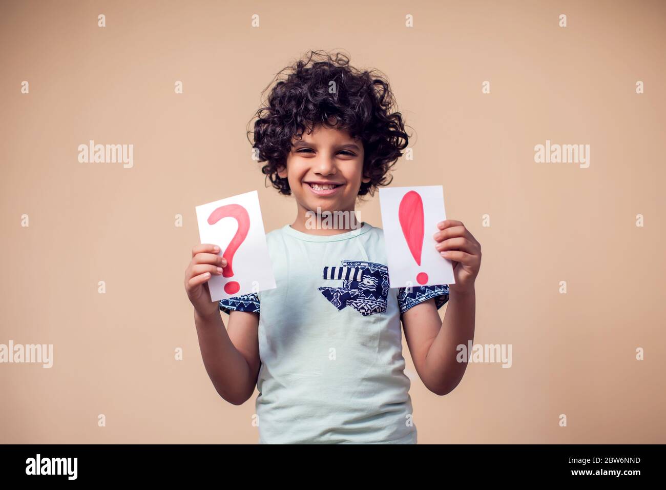 A portrait of kid boy holding cards with question mark and exclamation ...