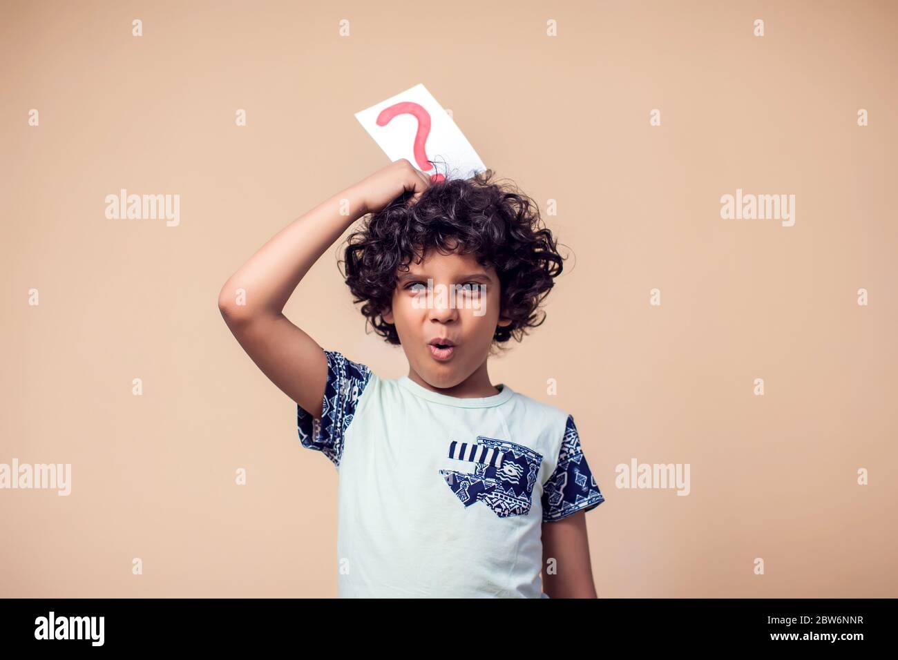 A portrait of kid boy holding cards with question mark. Childhood and ...