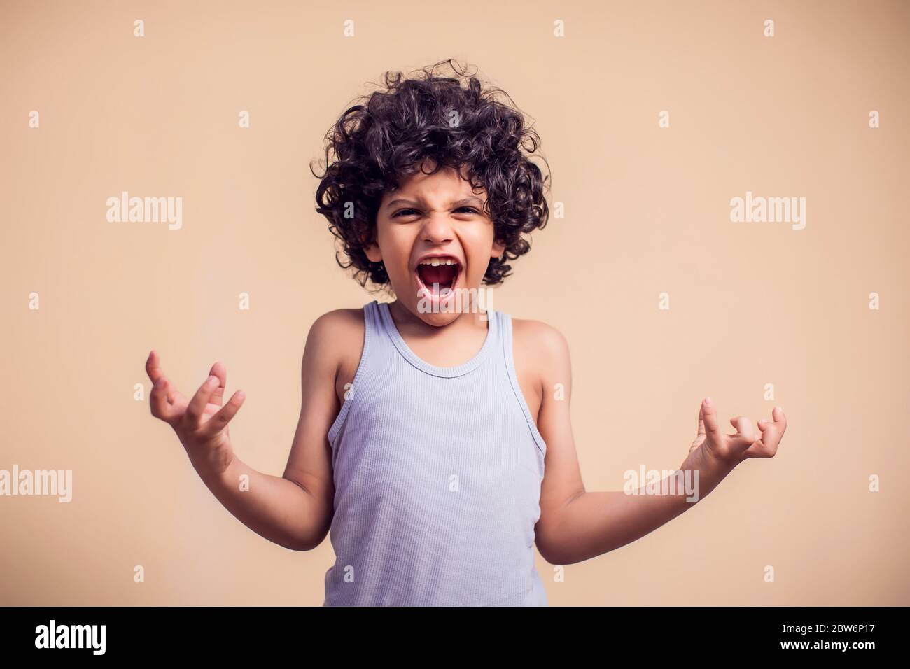 A portrait of angry kid boy with curly hair showing aggresion. Children ...