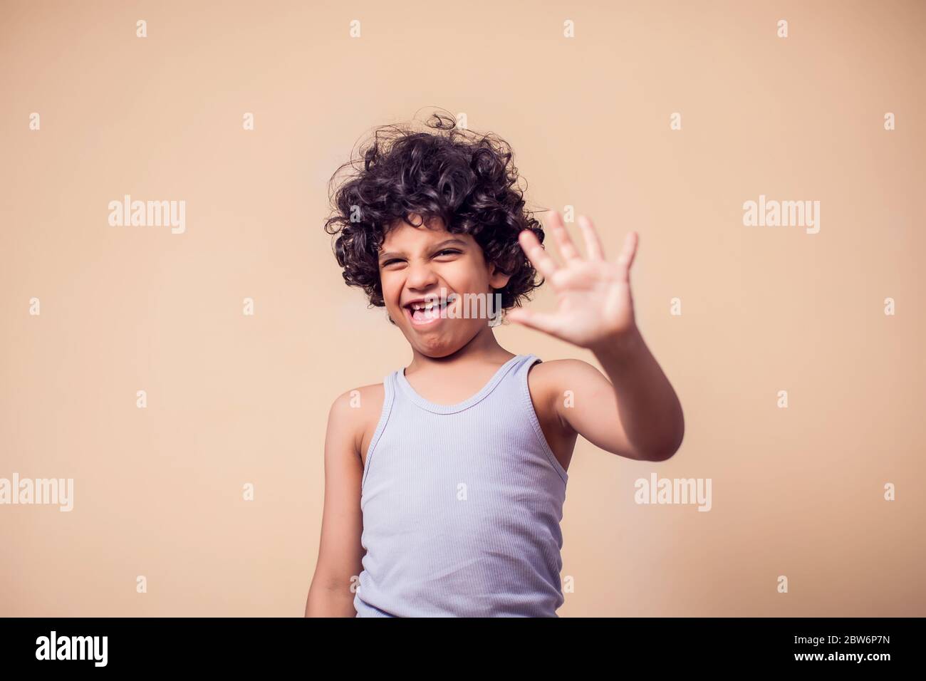 A portrait of angry kid boy with curly hair showing stop gesture ...