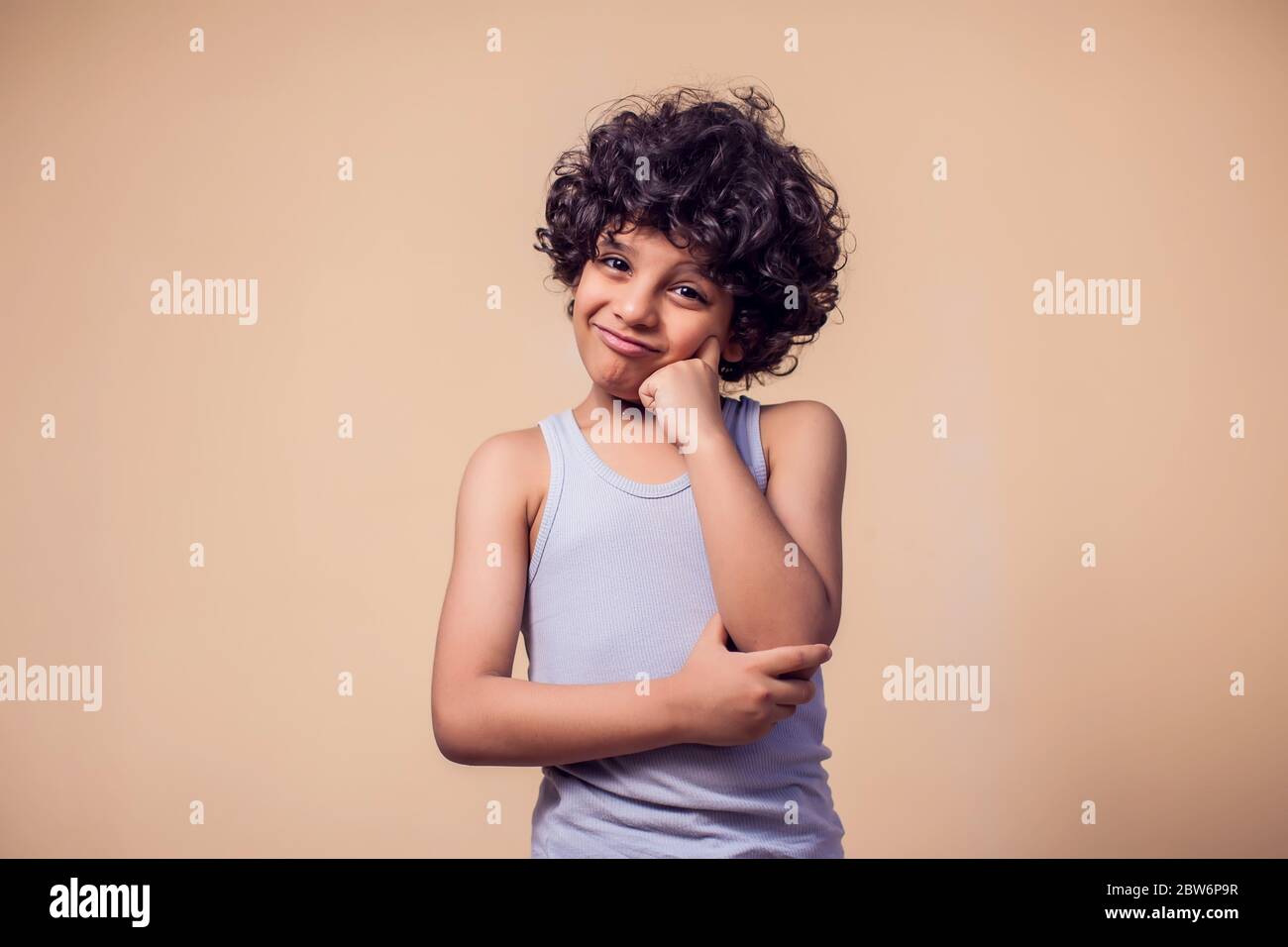 A portrait of pensive kid boy with curly hair. Children and emotions ...