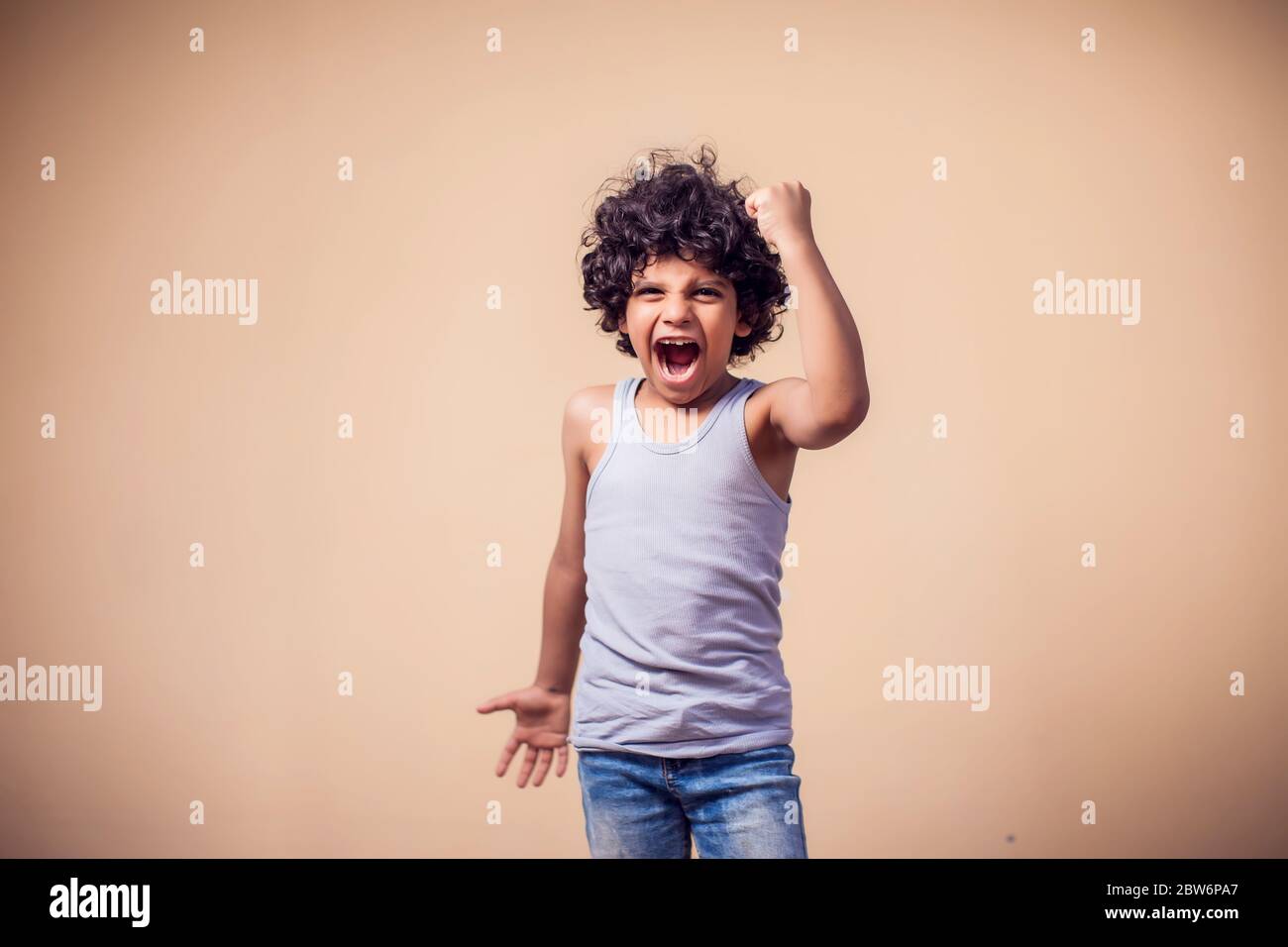 A portrait of angry kid boy with curly hair showing aggresion. Children ...