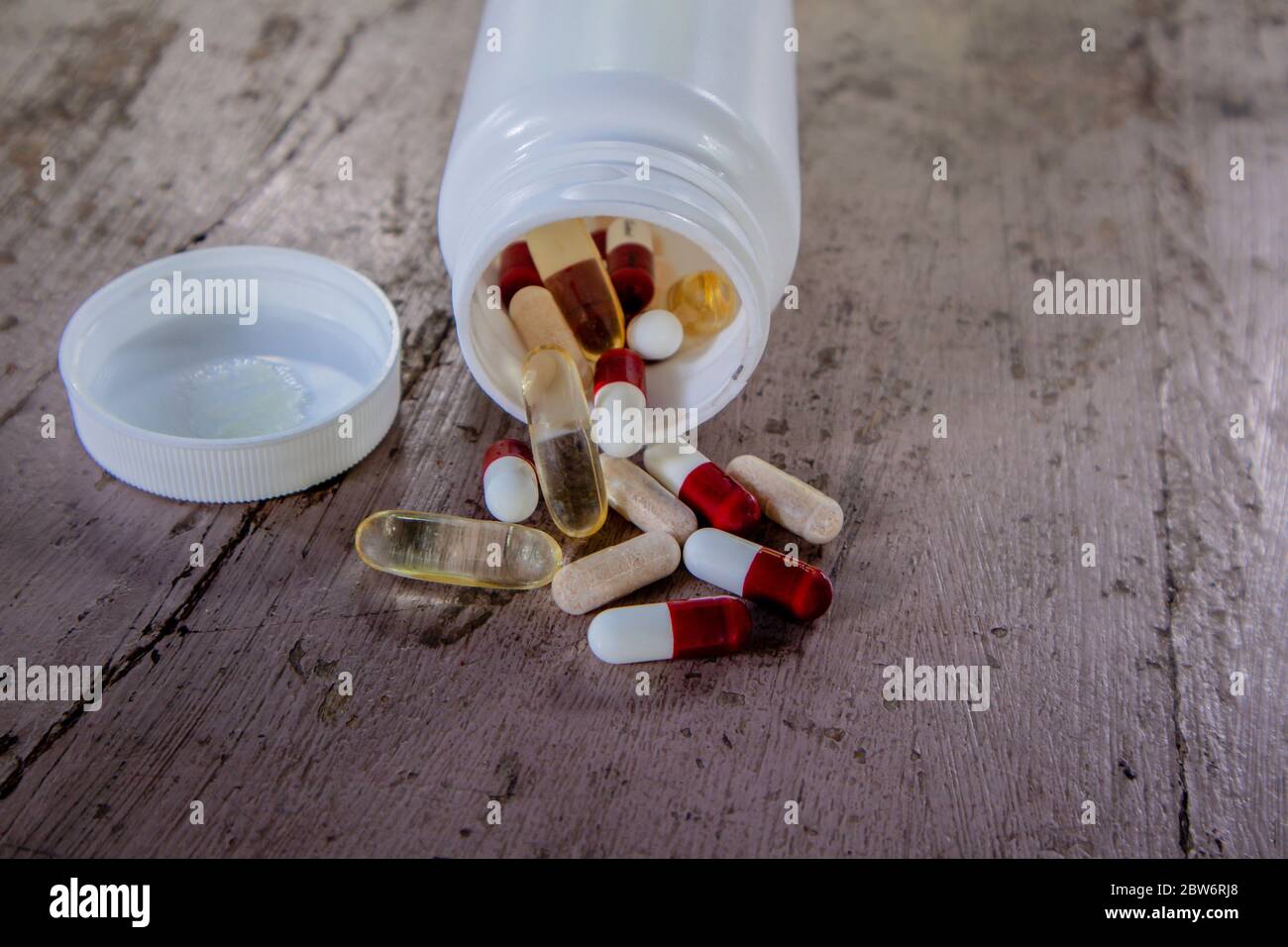 Medical tablets spilling out from plastic pill bottle on wooden ...