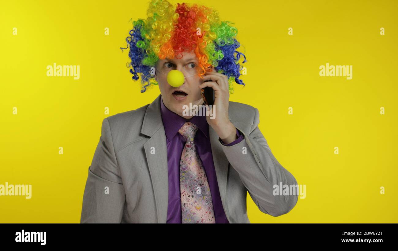 Scared clown manager office worker in wig and business suit at work ...