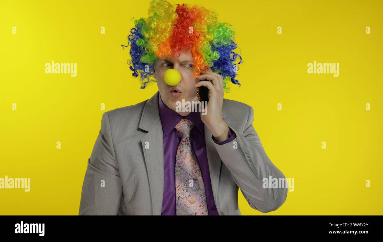 Scared clown manager office worker in wig and business suit at work ...