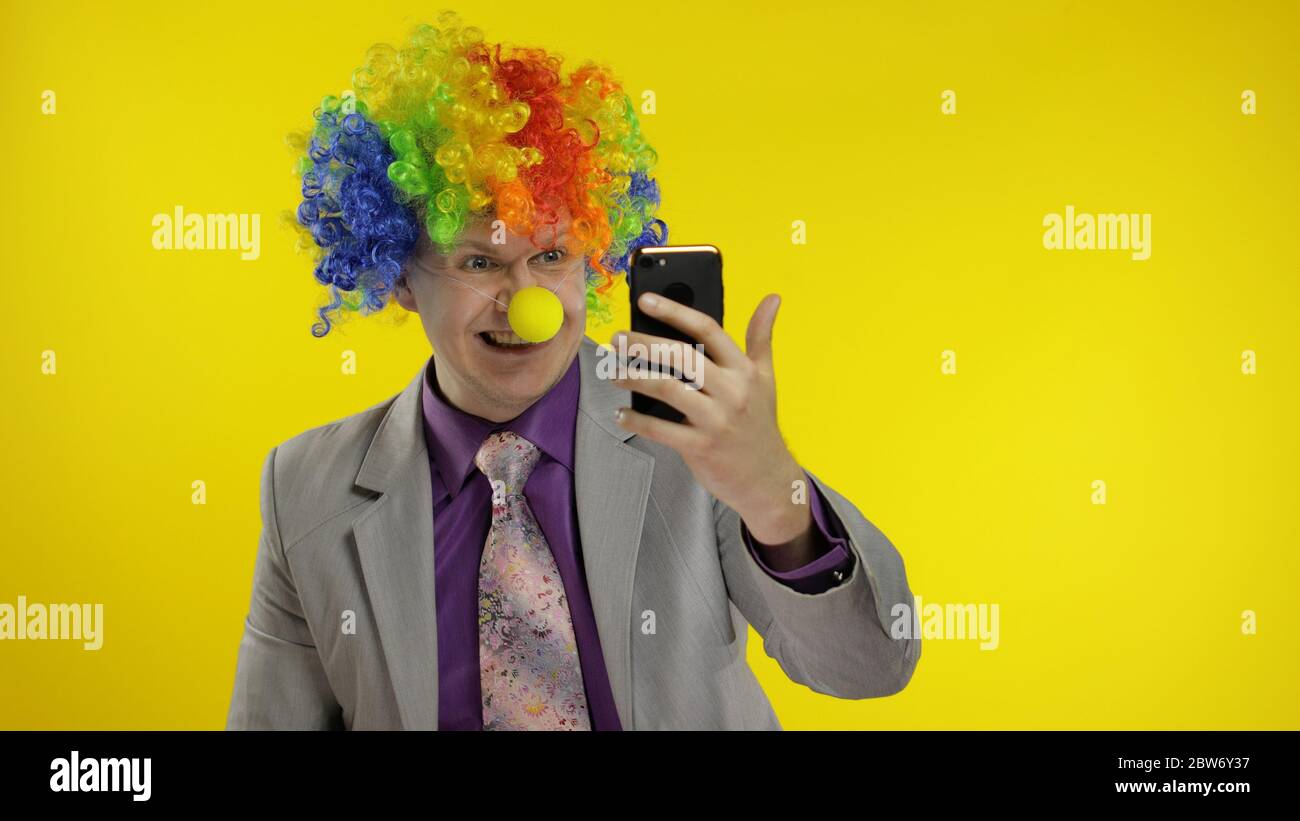 Happy clown director office worker in wig and business suit using app ...