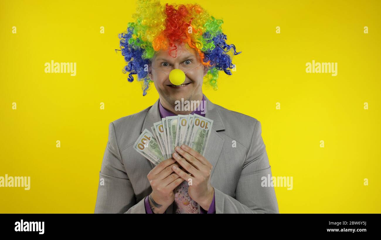 Happy clown manager office worker in wig and business suit with money ...