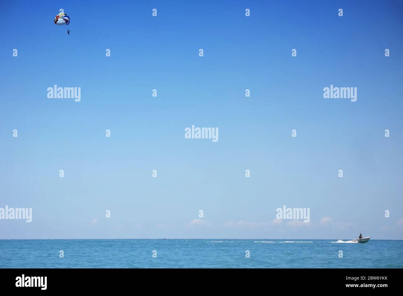 Water attraction - a boat tows a men on a parachute over the sea. Para ...